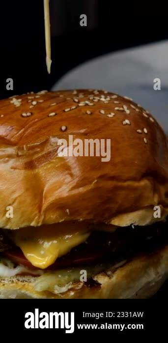 Slow motion image of inserting sticks into a soft burger bun, preparing ...