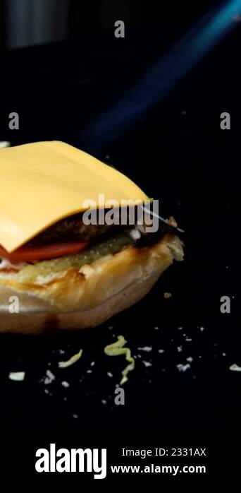 Image of the cheddar melting between the burgers with fire, slow motion ...