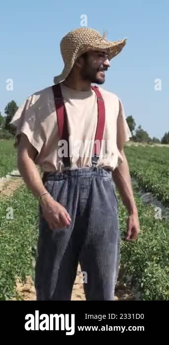 Farmer showing strength in field, male farmer with straw hat posing in ...