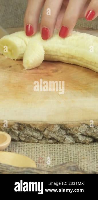 Image of woman hand slicing yellow banana on wooden cutting board ...