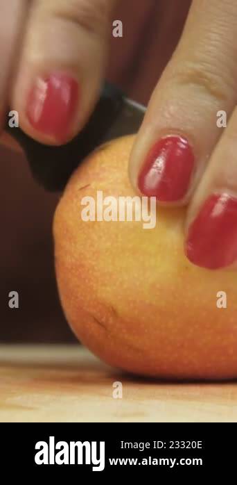 Close-up image of cutting pear with knife, woman holding knife dividing ...