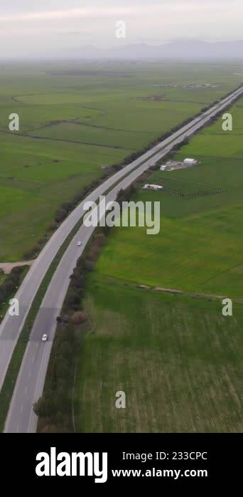 Drone view of the main road going through green fields, traffic density ...