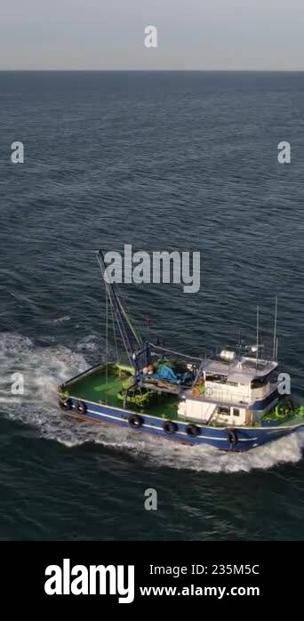 Drone view of small ship foaming in the sea, fishing boat fishing from ...