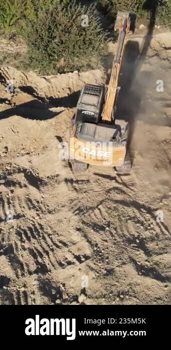 Aerial view of backhoe truck loading sand into container of sand field ...