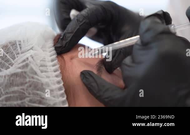 Beautician doctor makes botulinum toxin injection in the forehead of ...