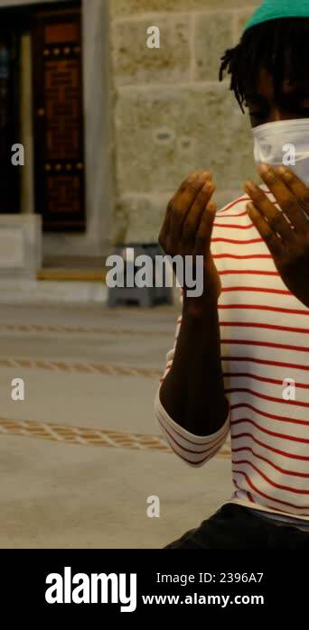 An African teenager with a mask on his face prays to Allah with his ...