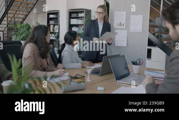 Young woman boss talking to group of employees during business meeting ...