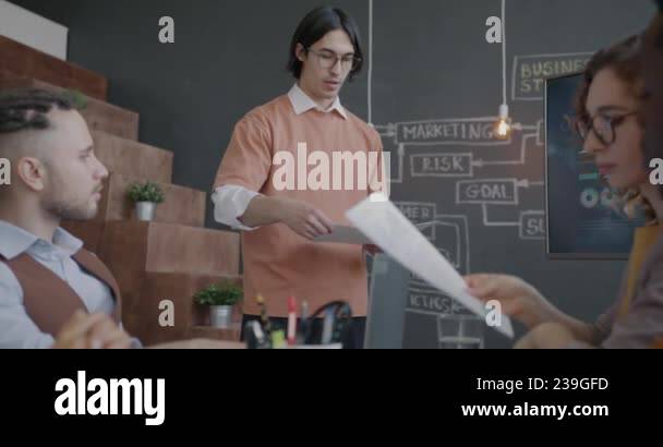 Businessman talking to diverse team giving papers leading business ...