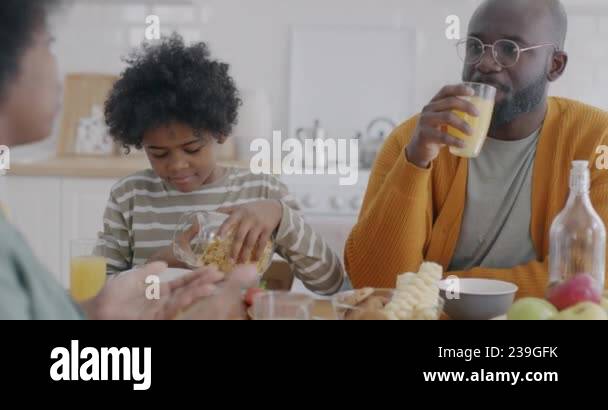 Happy African American child having breakfast with mother and father ...