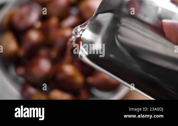 Washing nuts with fresh water from a steel pitcher. Chestnuts in blur ...