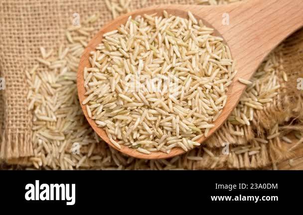 Coarse unprocessed basmati rice grains in wooden rustic spoon on rough ...