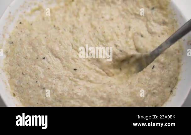 Mixing raw dough with plant-based ingredients in a white bowl. Spoon in ...