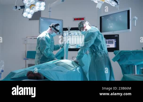 Surgeons in a brightly lit operating room performing a medical ...