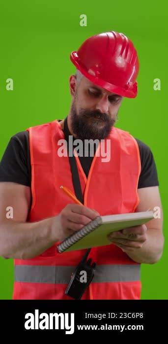 Vertical Screen: Construction worker in a red helmet and safety vest ...