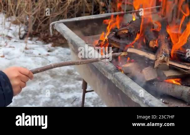 Child hand setting fire to wooden stick from barbecue. Unrecognized boy ...