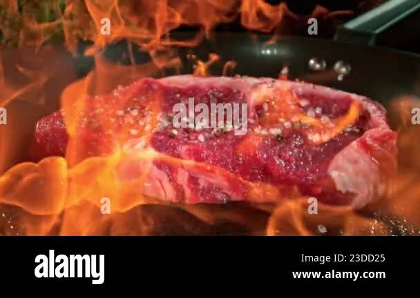 Super Slow Motion Shot of Raw Beef Steak Throwed into Fired up Pan with ...