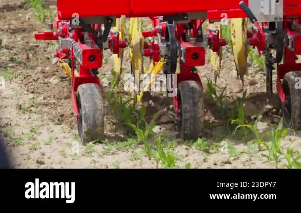 A red and yellow tractor is in the dirt. The tractor is used for ...