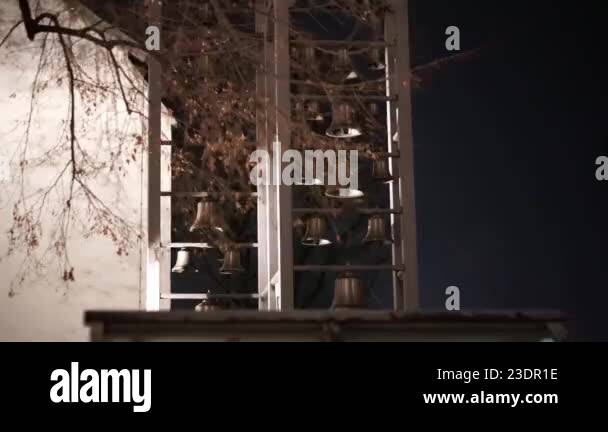 A large bell tower with many bells on it. The tower is lit up at night ...