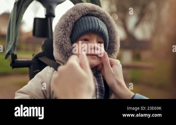 Close-up portrait of a smiling baby toddler boy in a stroller in winter ...