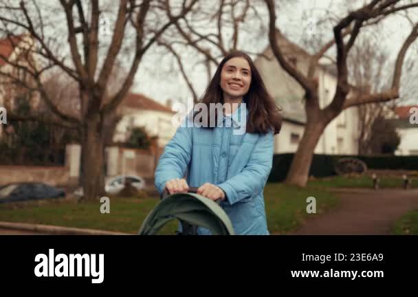 Close-up of a happy smiling young mother carrying a stroller with a ...