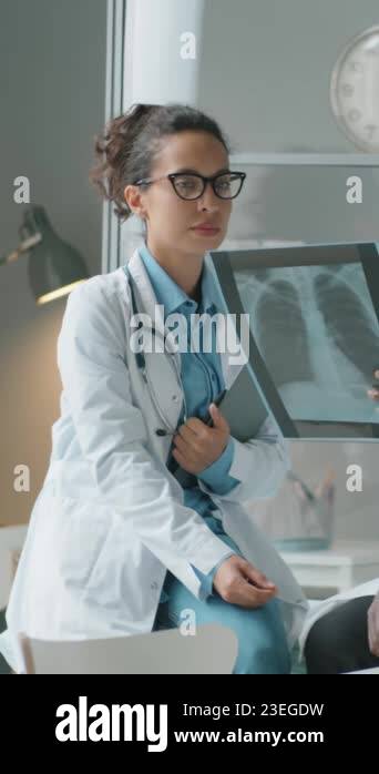 Vertical shot of female doctor sitting on medical couch in clinic ...