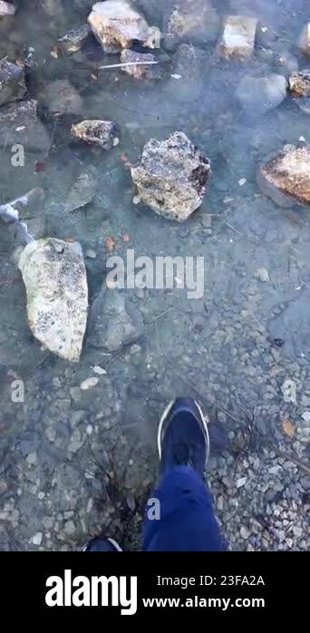 Mans foot stepping on an icy river and breaking the ice until it creaks ...