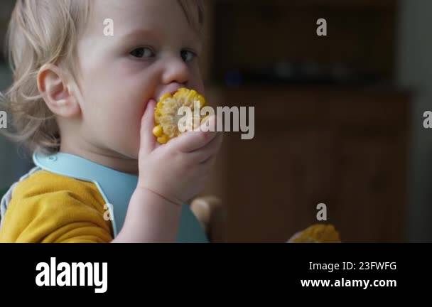 Toddler enjoys delicious corn snack, radiating happiness and curiosity ...
