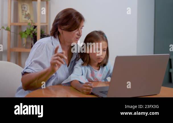 Young girl and her grandmother engage with laptop at home discovering ... Young girl and her grandmother engage with laptop at home discovering ...