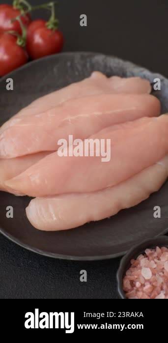 Raw chicken fillet cut into strips with spices and herbs on a wooden ...