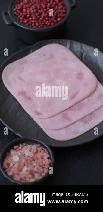 Boiled ham with salt and spices cut into slices on dark concrete ...