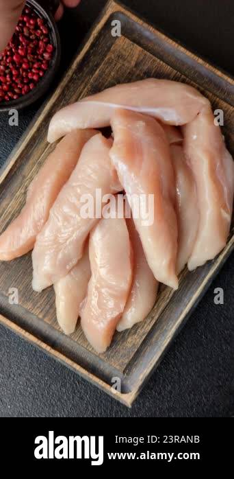 Raw chicken fillet cut into strips with spices and herbs on a wooden ...