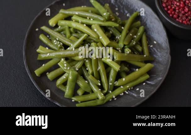 Steamed green beans on a plate with olive oil, sesame seeds, salt and ...