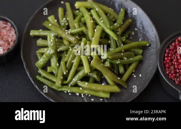 Steamed green beans on a plate with olive oil, sesame seeds, salt and ...