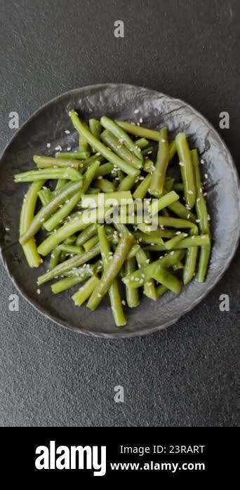 Steamed green beans on a plate with olive oil, sesame seeds, salt and ...
