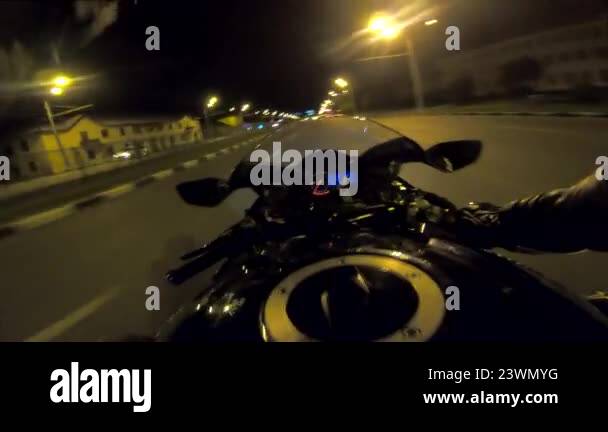 Male motorcyclist riding on modern sport bike in illuminated city empty ...
