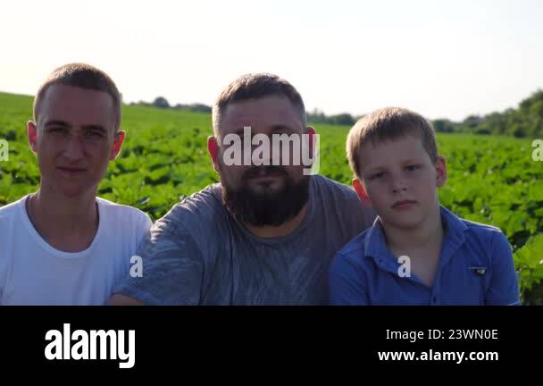 Portrait of daddy and children at cultivated meadow. Young father with ...