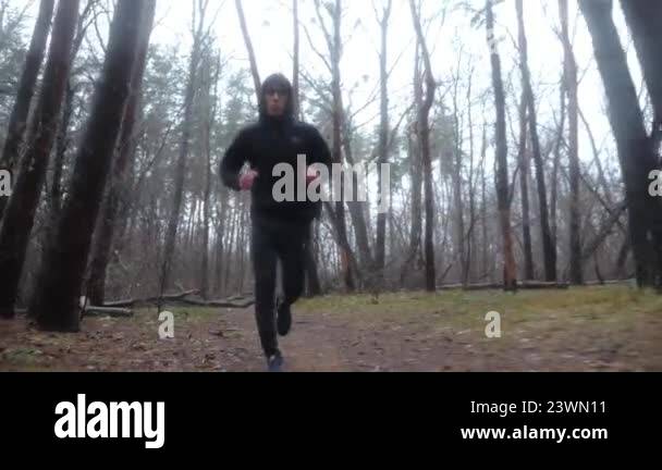 Sporty male runner jogging along trail at autumn forest. Young ...