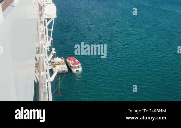 Capture the moment a small boat approaches a massive cruise ship to ...
