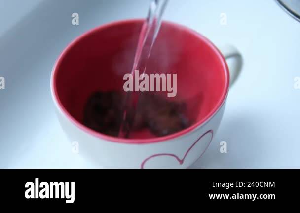 Dry cocoa powder in a cup is poured with boiling water, steam flows ...