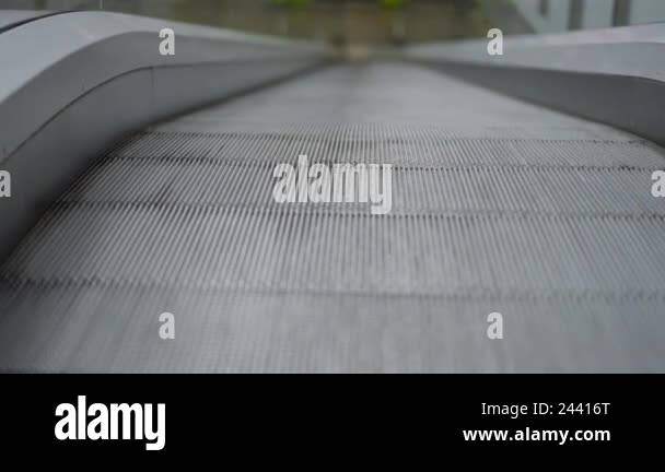 A close-up view of a moving escalator in a modern shopping mall. The ...