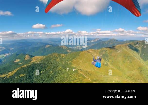 Thermal Flying on red wing above green alps mountains in beautiful ...