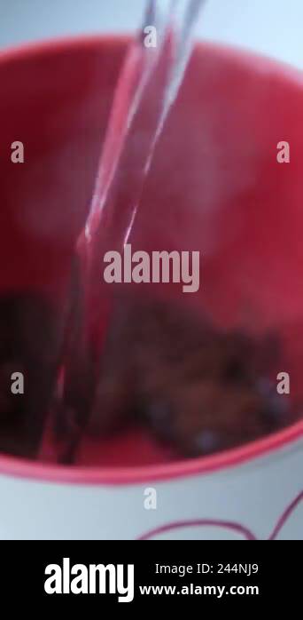 Dry cocoa powder in a cup is poured with boiling water, steam flows ...