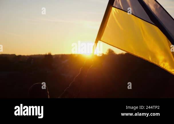 Male military in uniform lifting blue-yellow banner in honor of the ...