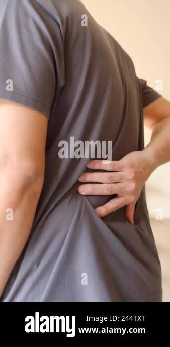 A person clutching their lower back, indicating pain or strain. This ...