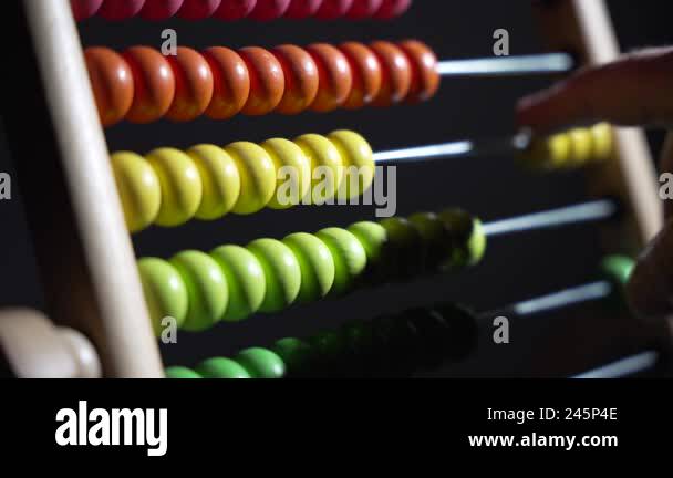 A man counts on a wooden abacus. A wooden abacus with colored beads on ...