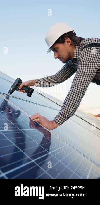 A skilled worker uses a cordless drill to securely install a solar panel, ensuring optimal ...