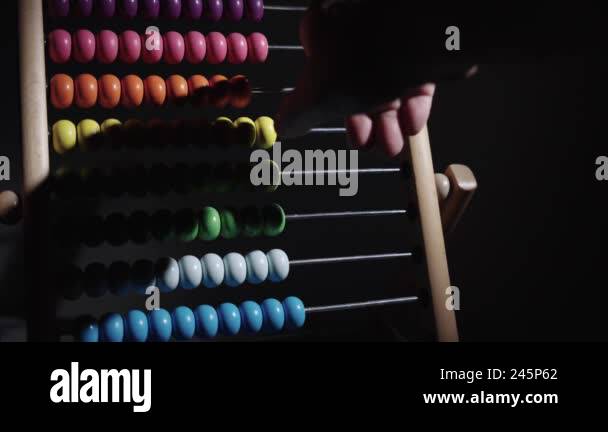A man counts on a wooden abacus. A wooden abacus with colorful beads on ...