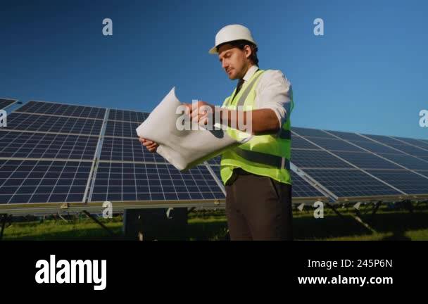 An engineer in a helmet and safety vest carefully reviews installation ...