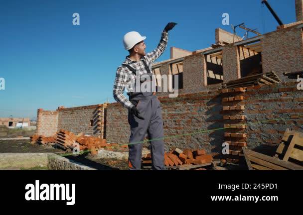 A construction supervisor in safety gear gestures while overseeing the ...