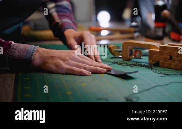 A focused leatherworker creating a belt in a workshop filled with tools ...